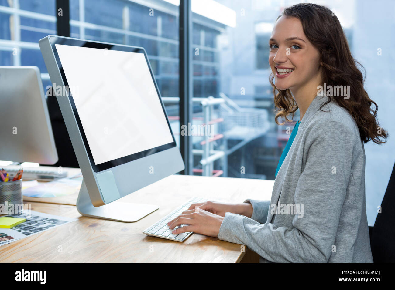 Portrait of female graphic designer working over computer at desk in ...
