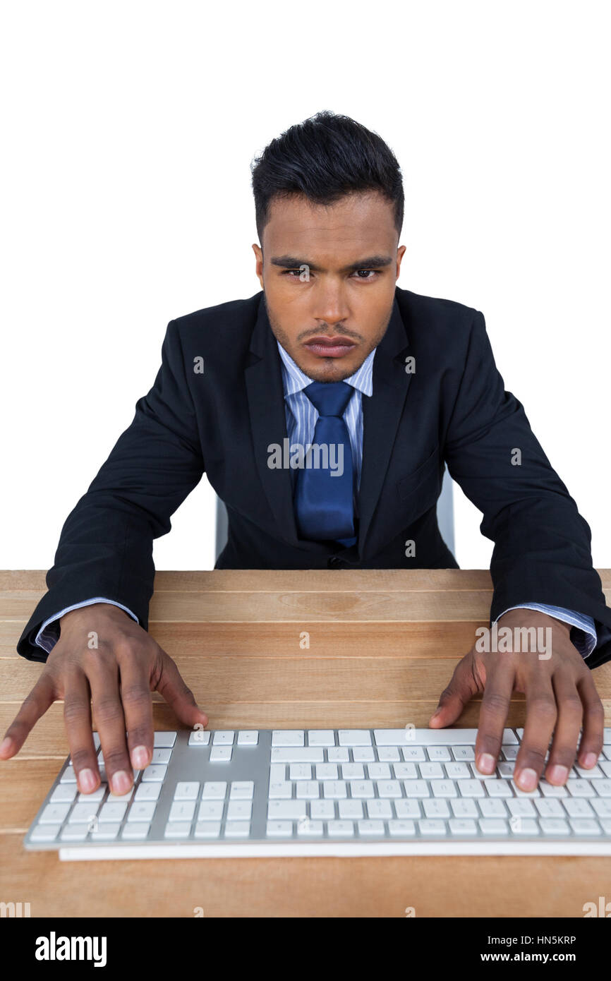 Portrait of businessman typing on keyboard at desk against white ...