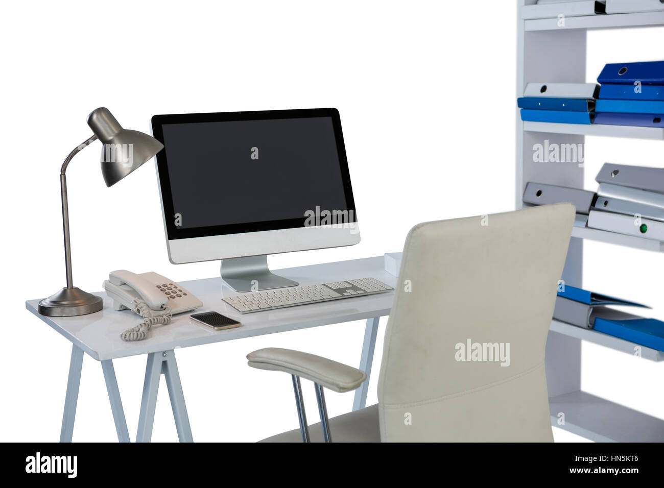 Computer with telephone and mobile phone at desk against white ...
