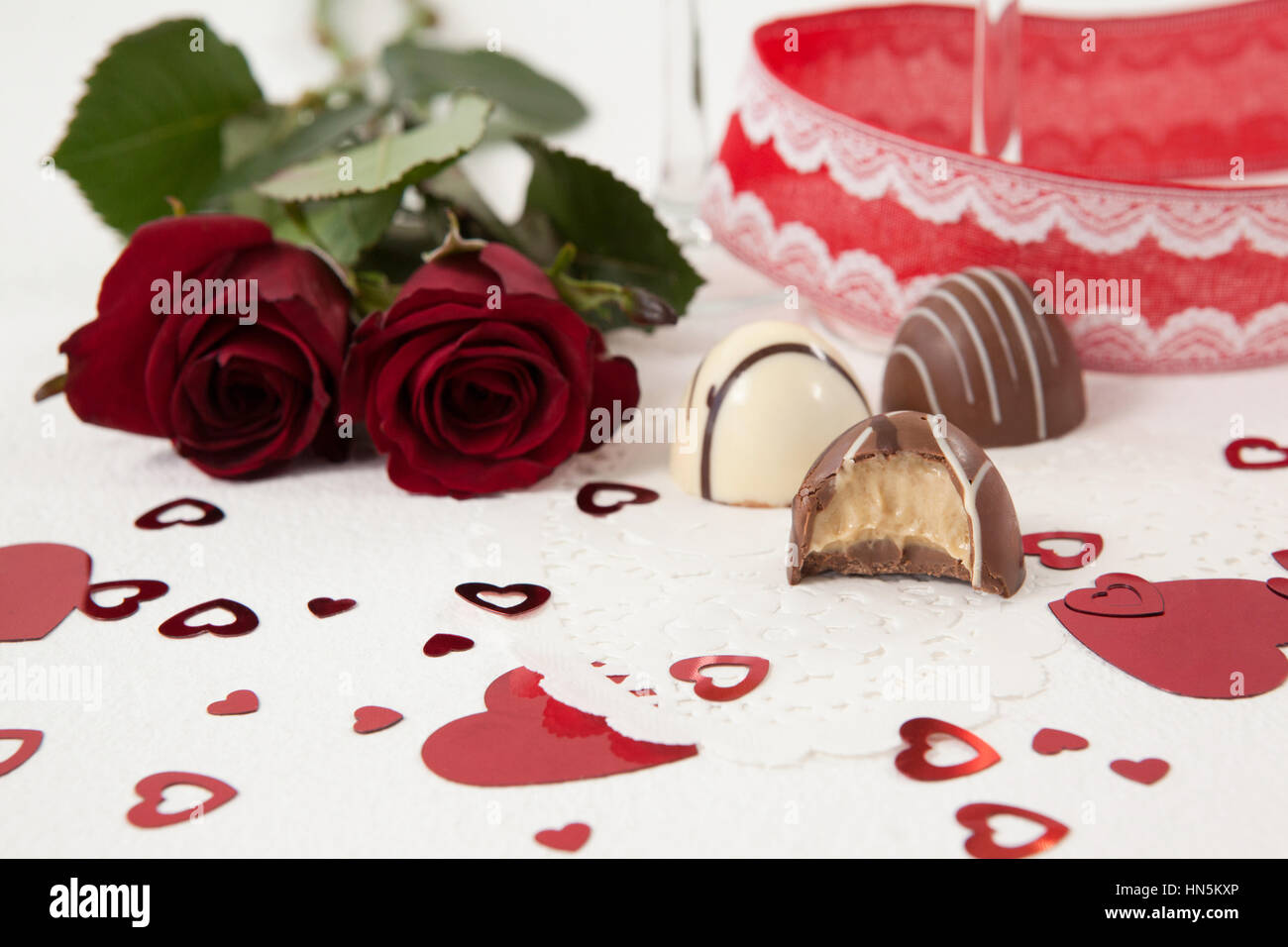 Bunch of roses and assorted chocolate surrounded by heart decoration ...