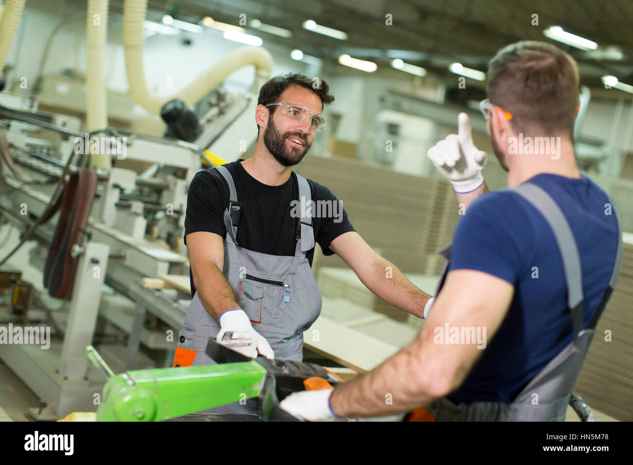 Two handsome young men working in lumber workshop Stock Photo - Alamy