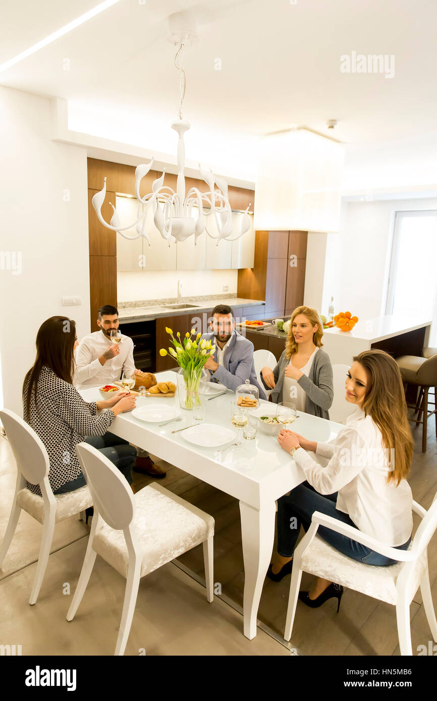 Group of young friends having dinner at home and toasting with white ...