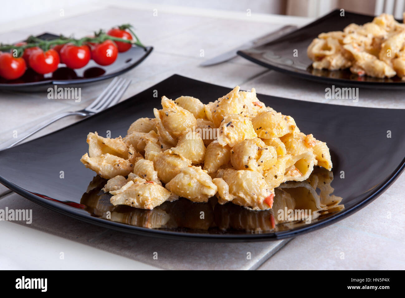 tasty pasta black large plate on the dining table Stock Photo - Alamy