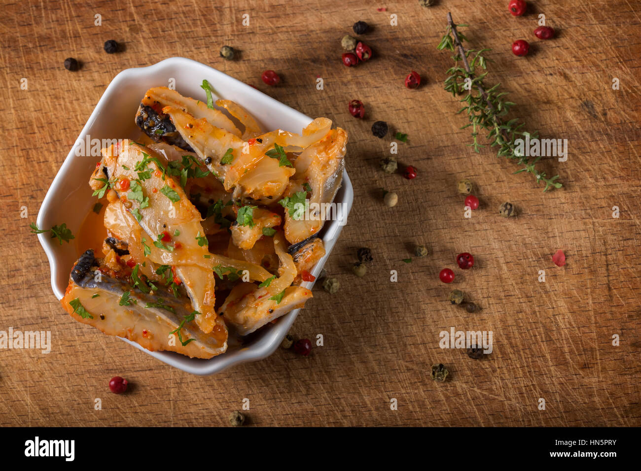 Marinated herring fish with onion and tomato sauce in white bowl over ...