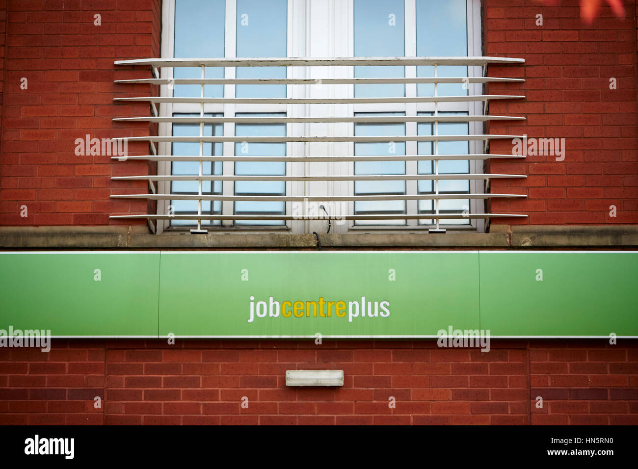 Green sign on the exterior architecture wall of Job Centre Plus doorway ...