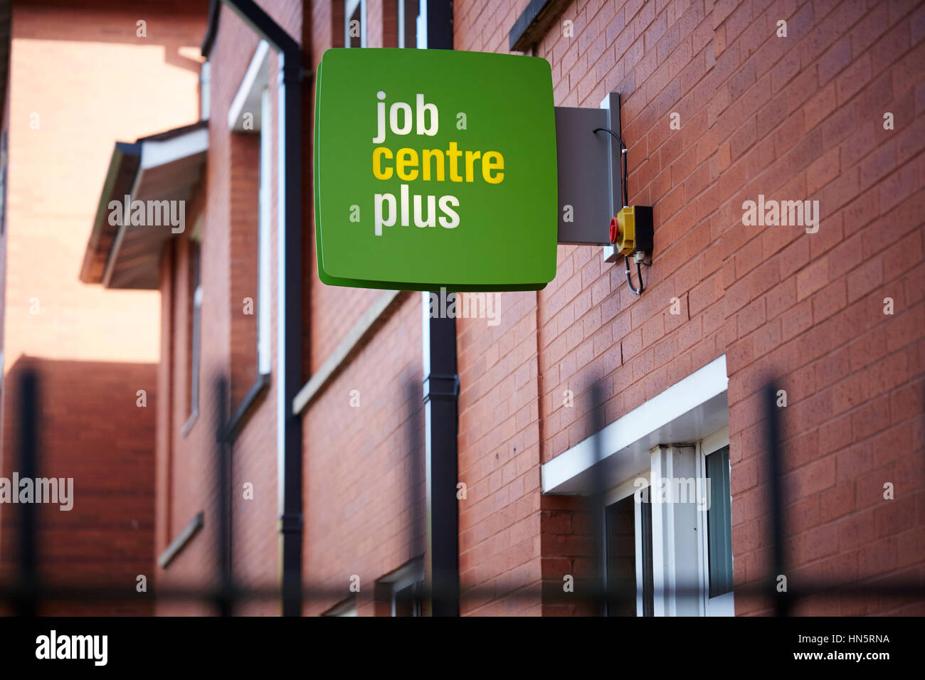 Green sign on the exterior architecture wall of Job Centre Plus doorway ...