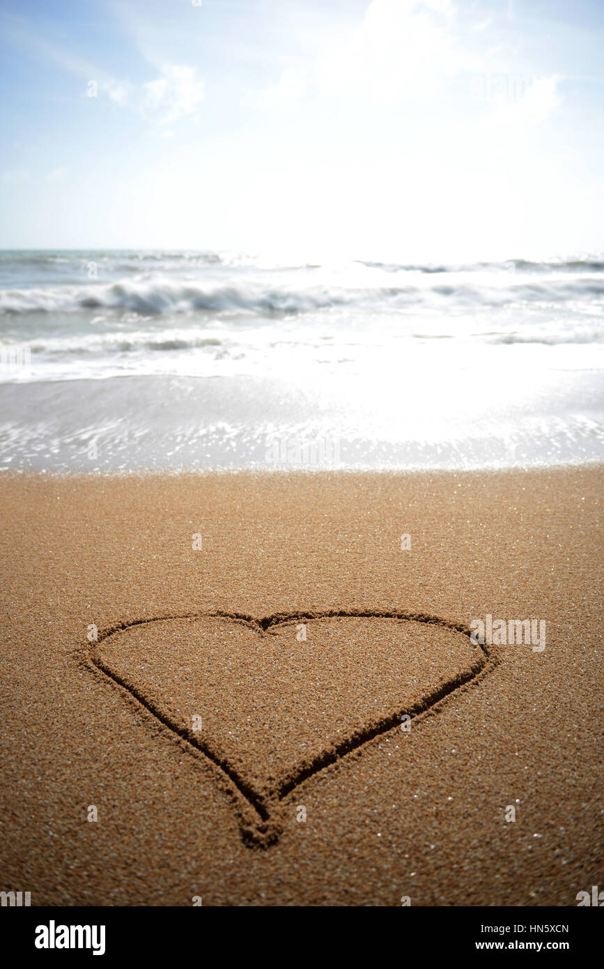 Love heart drawn in the sand, with ocean waves in the background Stock ...