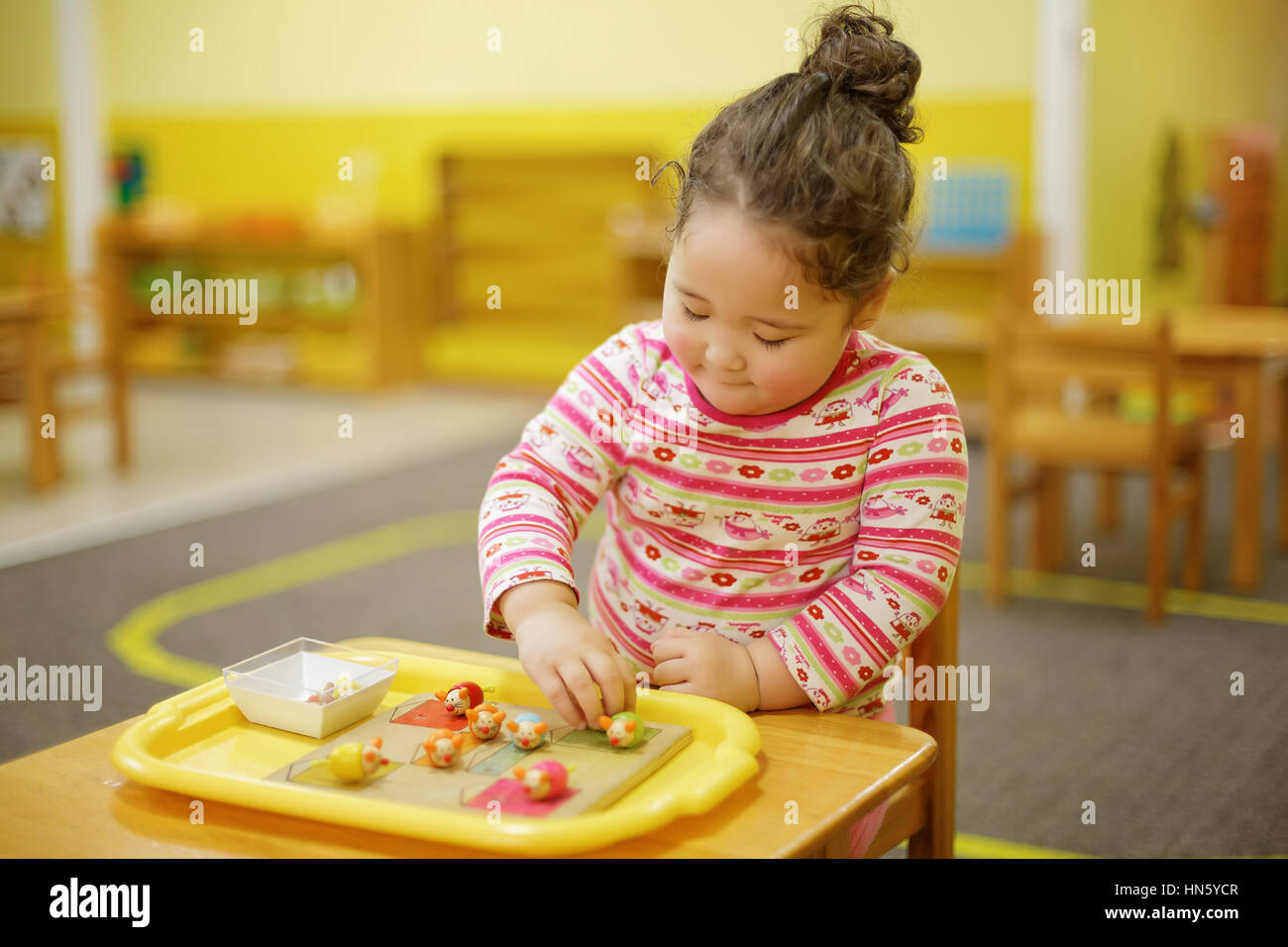 kazakh curly girl playing in kids development center Stock Photo - Alamy