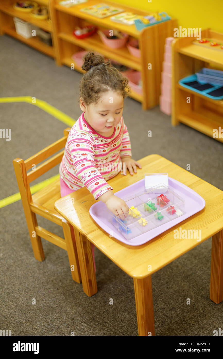 kazakh curly girl playing in kids development center Stock Photo - Alamy