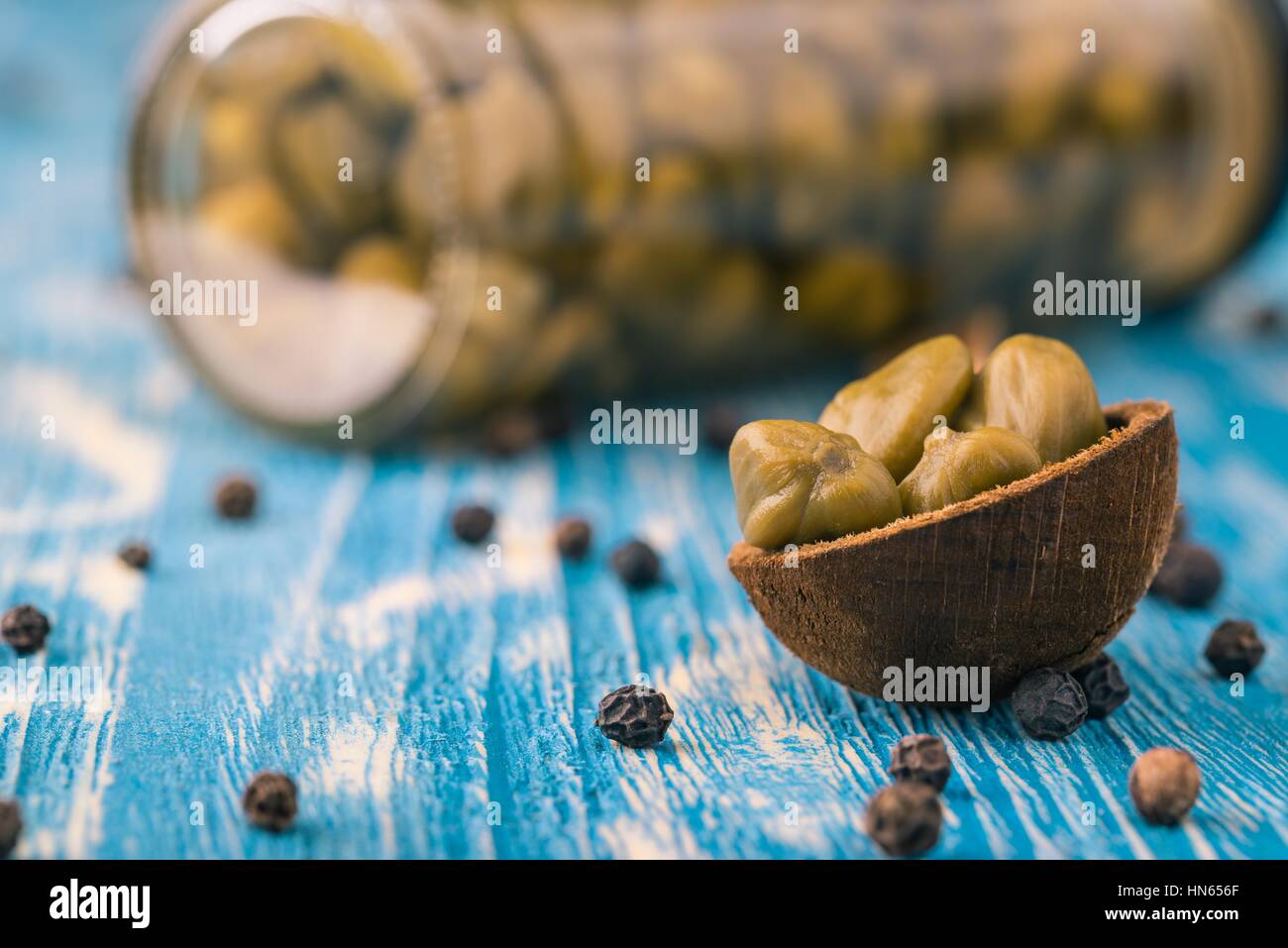Horizontal photo of pickled green capers. Few pieces of edible blooms ...