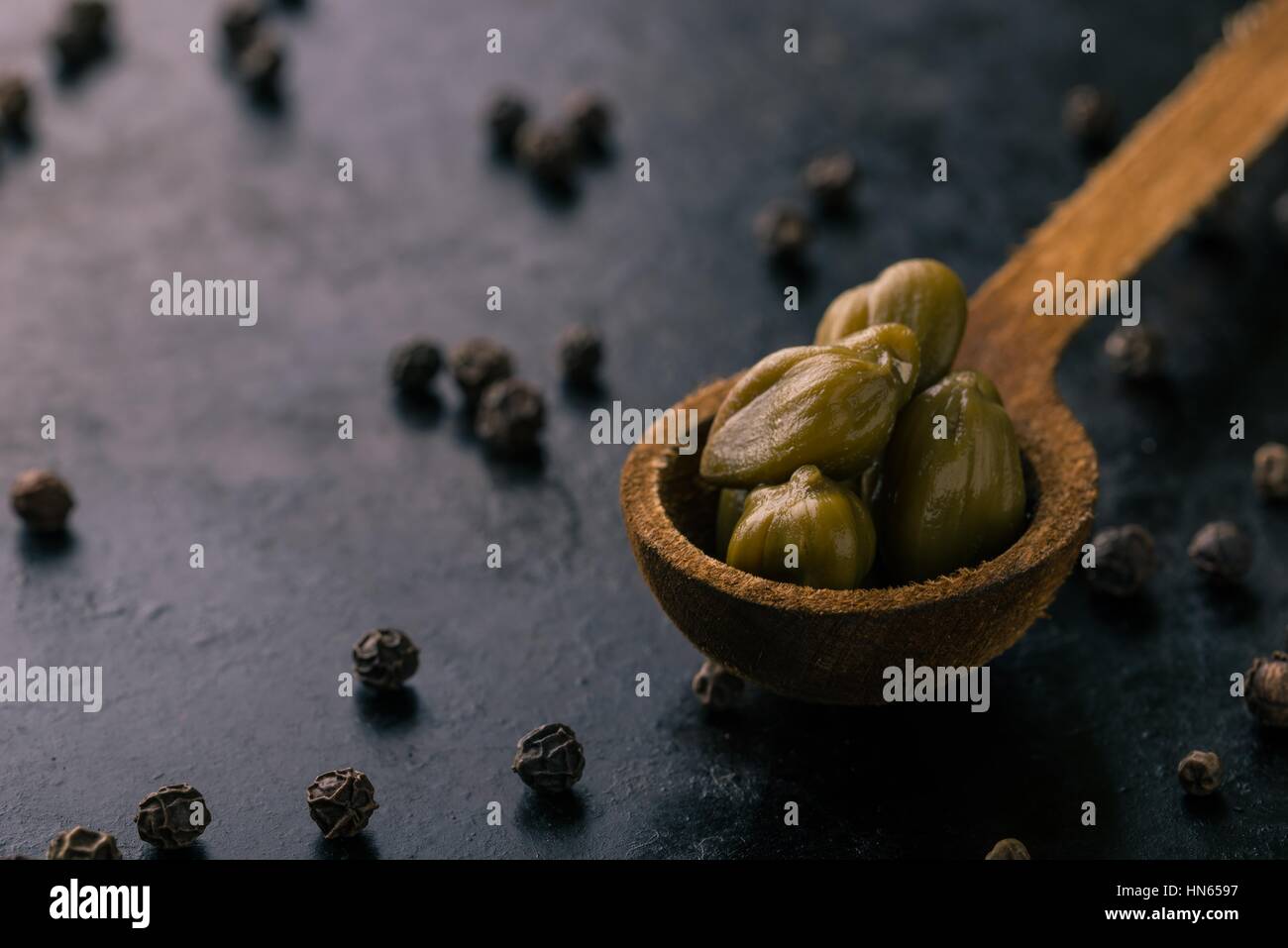 Horizontal photo of pickled green capers. Few pieces of edible blooms ...