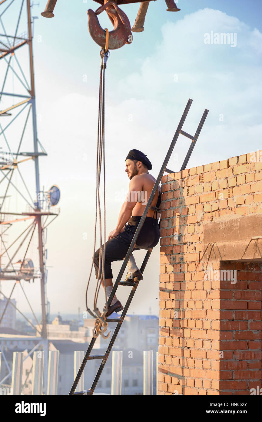 Man sitting on ladder on high Stock Photo - Alamy