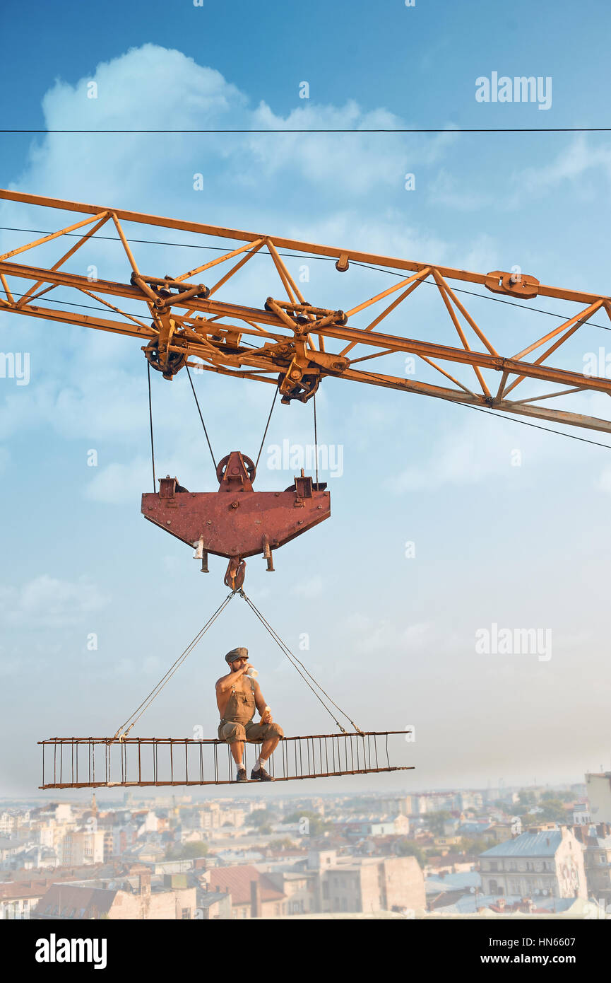 Crane holding construction builder eating Stock Photo - Alamy