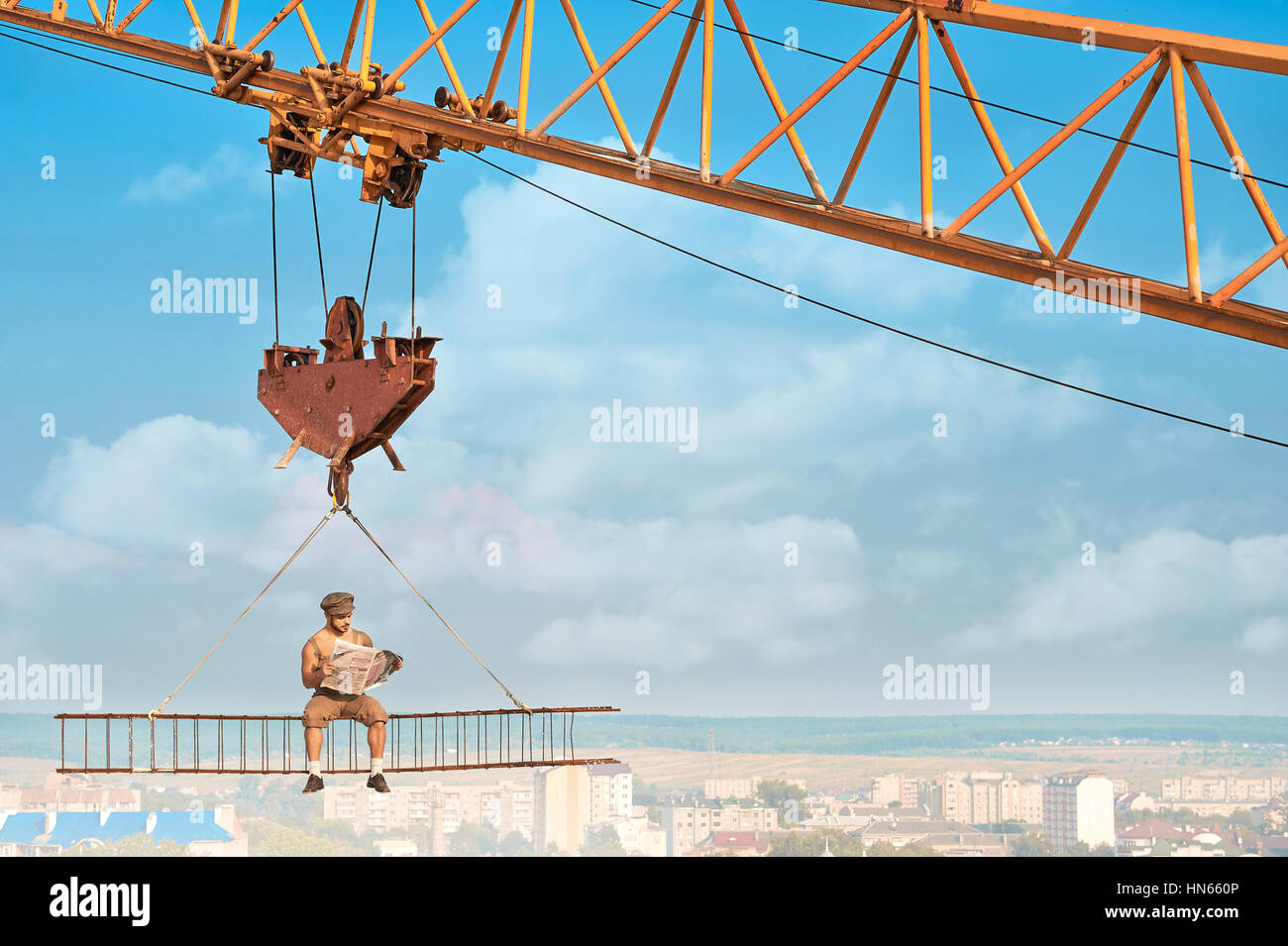 Crane holding iron construction, where sitting builder Stock Photo - Alamy