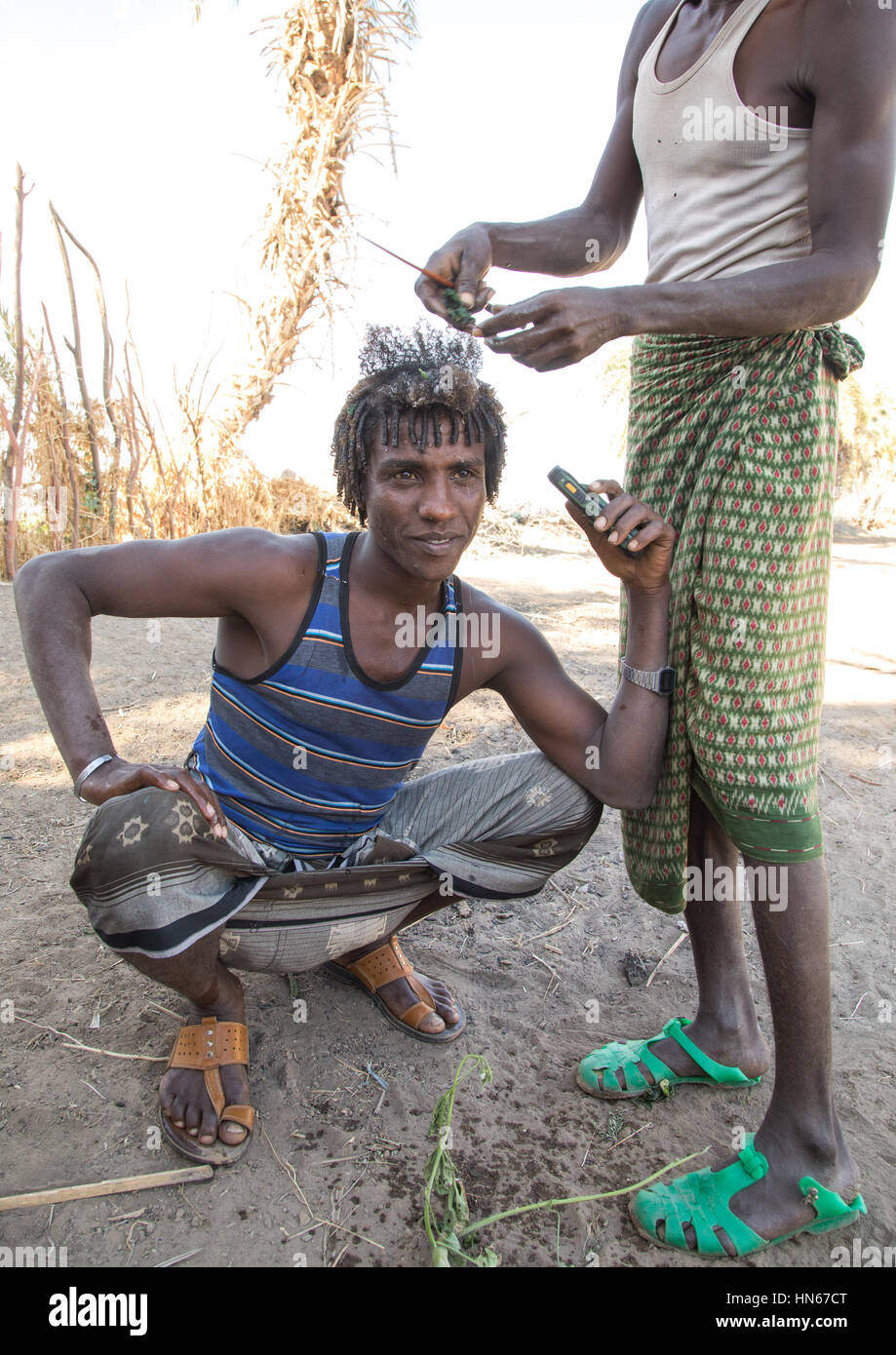 Afar man having a traditional hairstyle with a stick to make curly hair ...