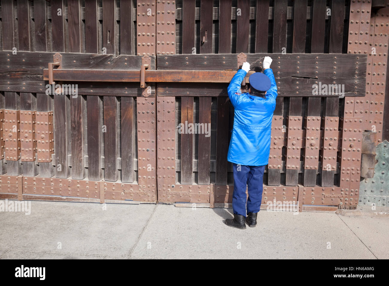 Kyoto, Japan - March 19, 2012: A security guard in a blue uniform locks ...