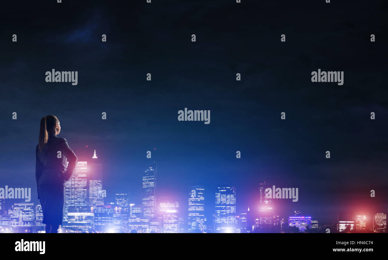 Rear view of elegant businesswoman viewing lights of night city Stock ...