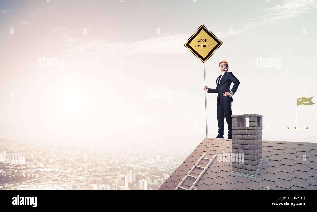 Man holding safety sign indicating under construction notice. Mixed ...