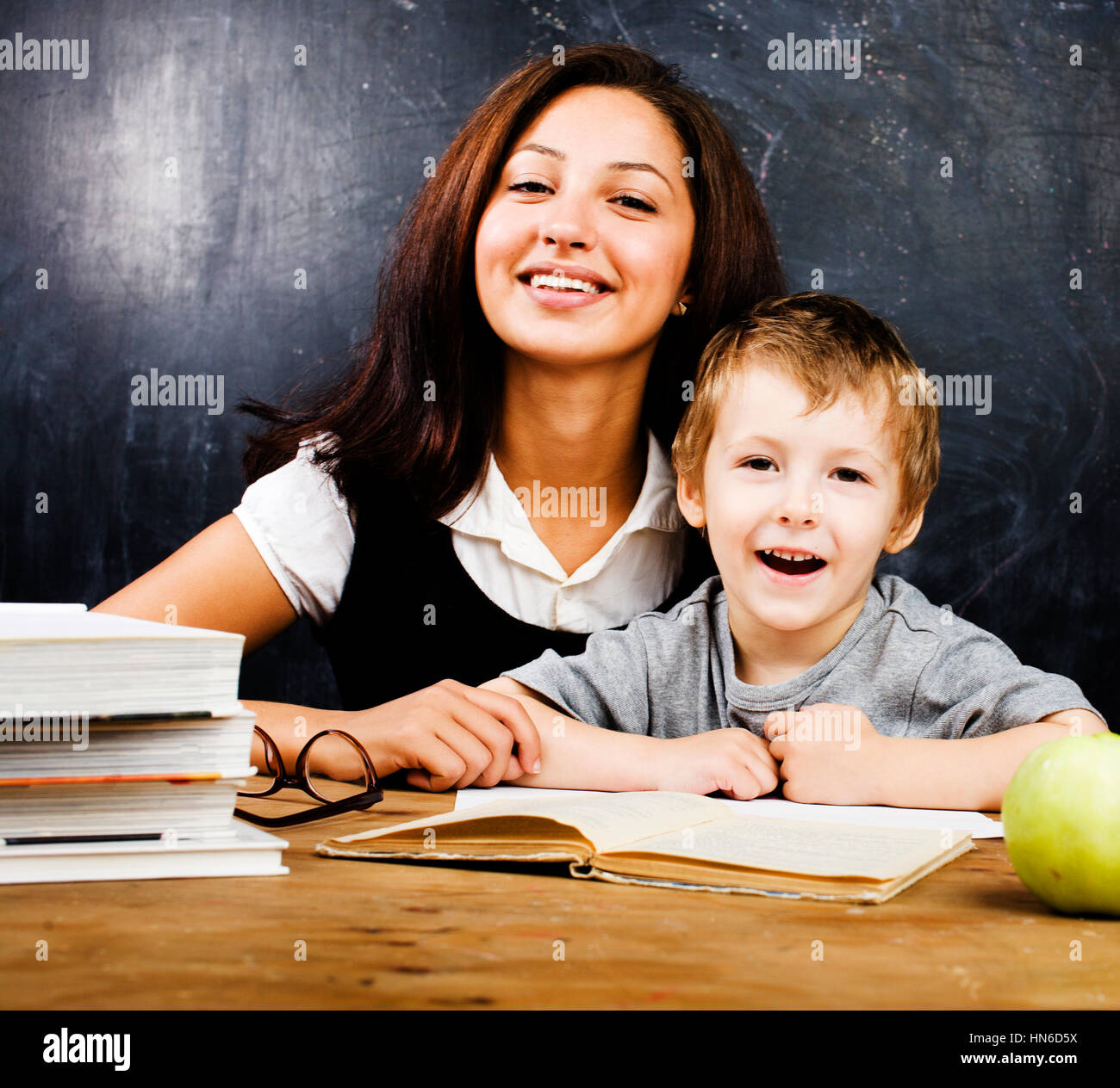 little cute boy with teacher in classroom at desk Stock Photo - Alamy