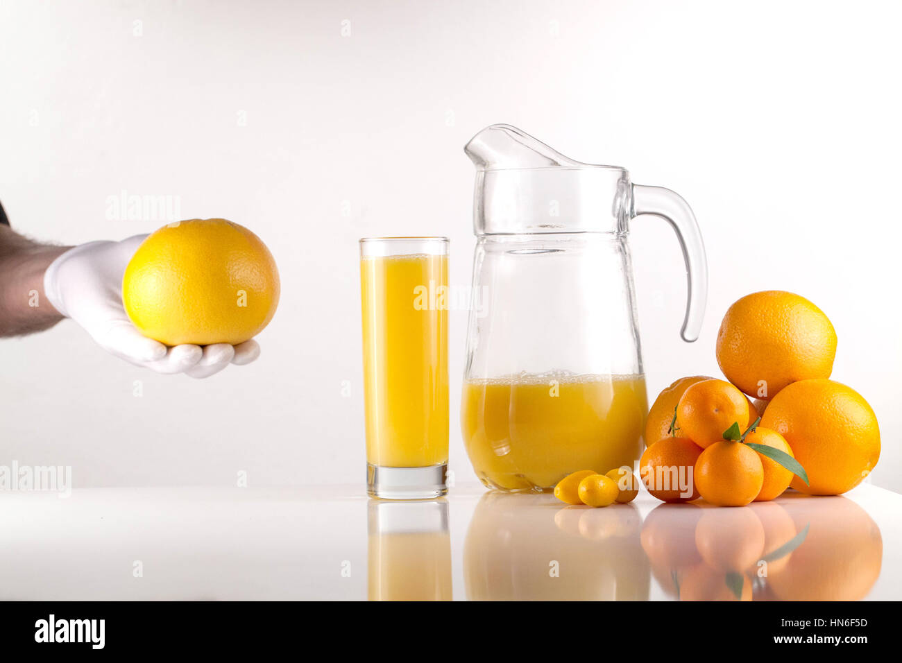 Orange in hand near glass of orange juice and pyramid of oranges Stock ...