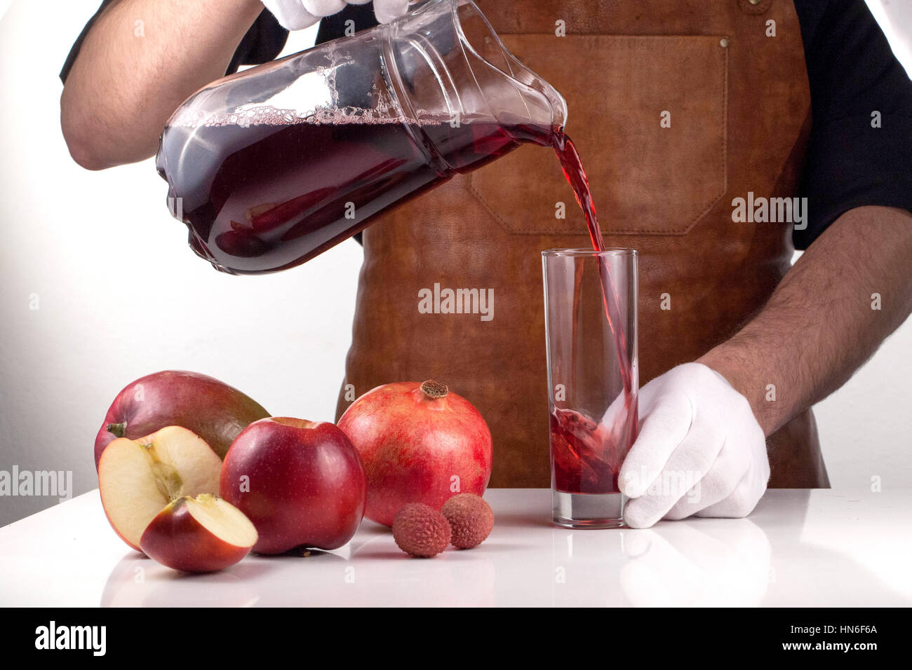 Man pouring juice into a glass. Composition of red fruits on a white ...