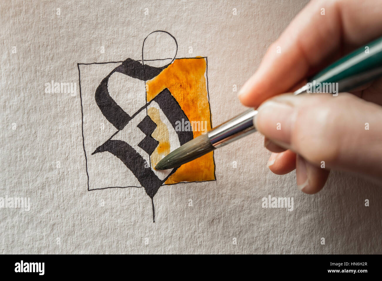 Calligraphy studio, hand paints surface with brush, letter S on torchon ...