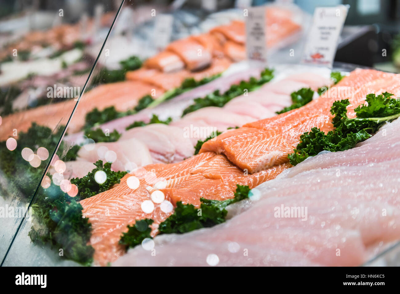 Seafood stand with cuts and filets of salmon and tuna on ice behind ...
