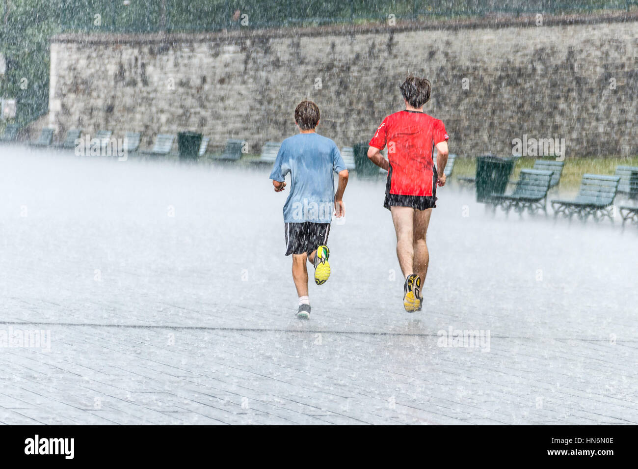 Quebec City, Canada - July 27, 2014: Two guys run in the heavy rain on ...