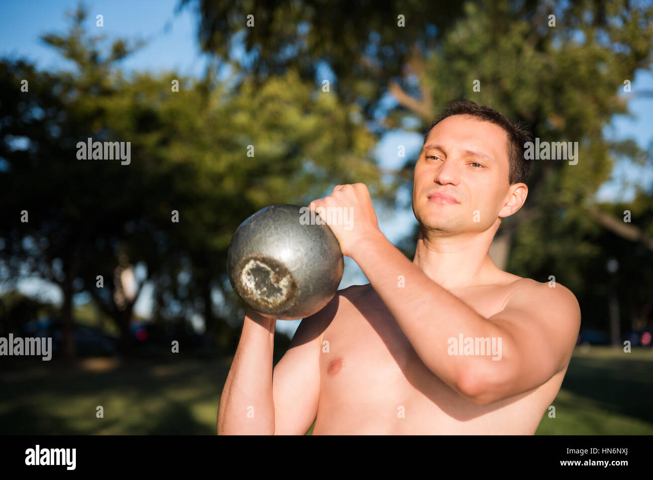 Closeup of fit muscular man lifting heavy kettlebell over the shoulder ...