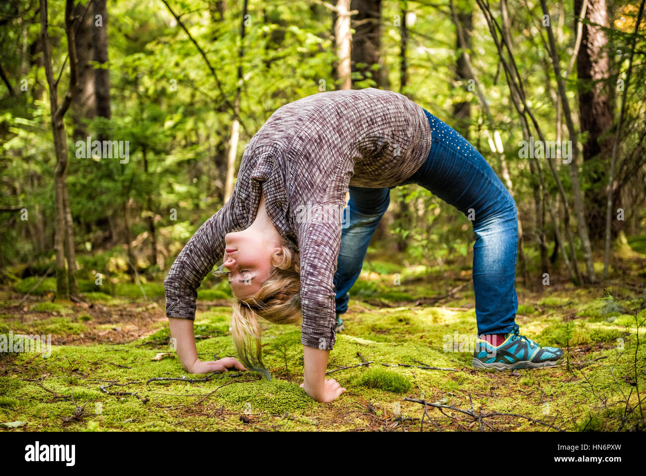 Young woman in back bend arch pose in mossy forest Stock Photo - Alamy