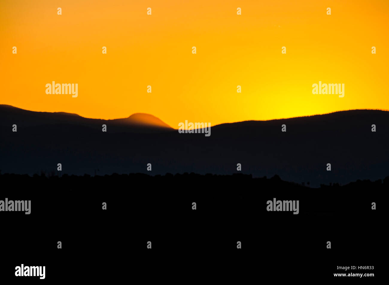 A colorful sunset in Santa Fe, New Mexico with a sun hiding behind ...