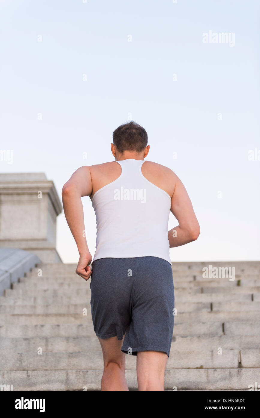 Back of young fit man running up steps outside during workout Stock ...