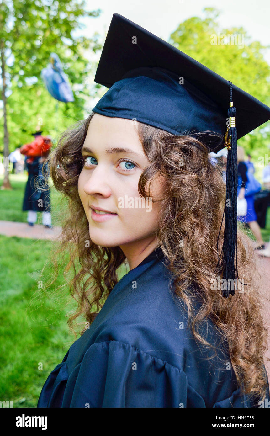 Portrait of young happy woman at college graduation ceremony in gown ...