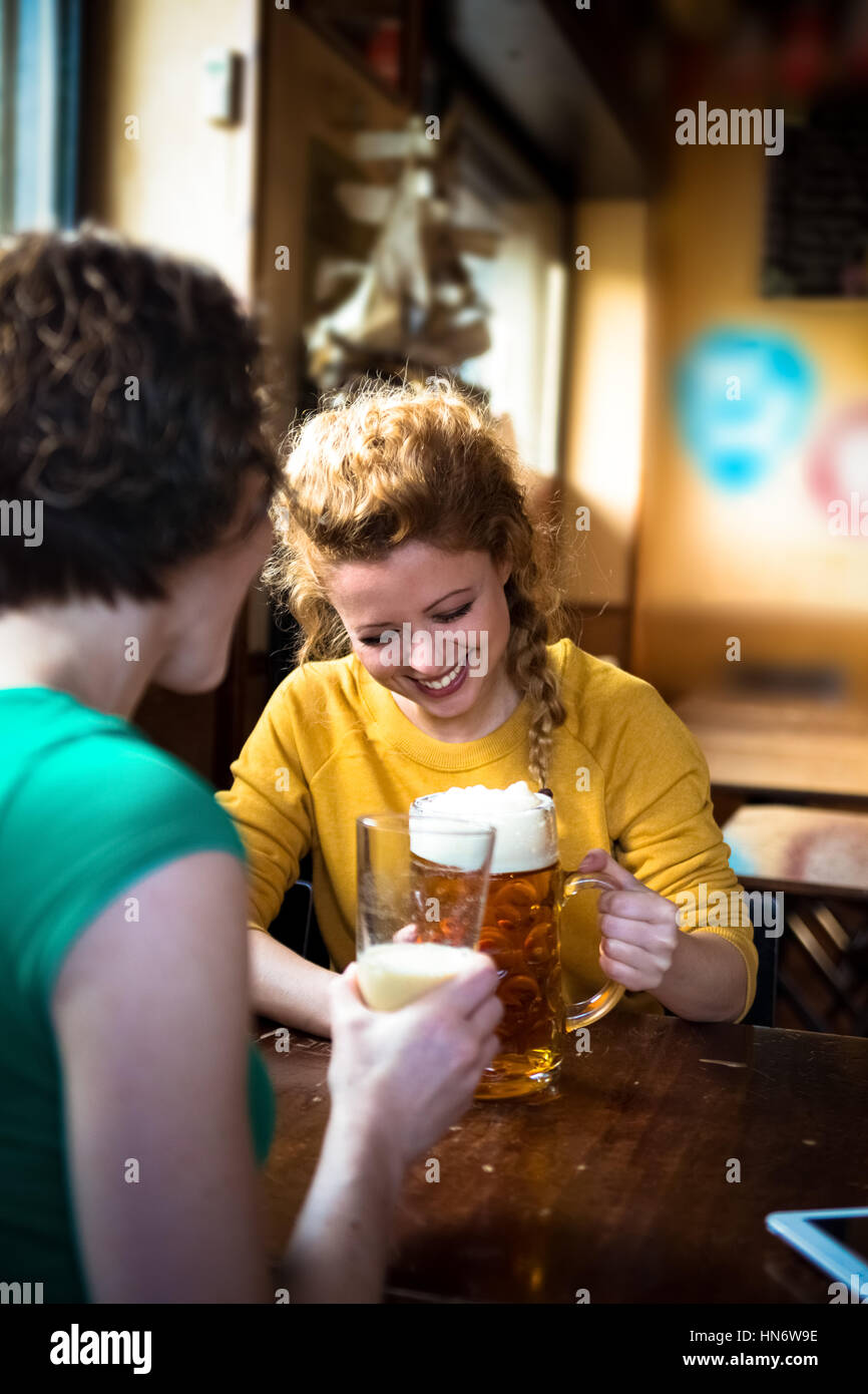 two friends getting toghether drinking beer and laughin, indoor setting ...
