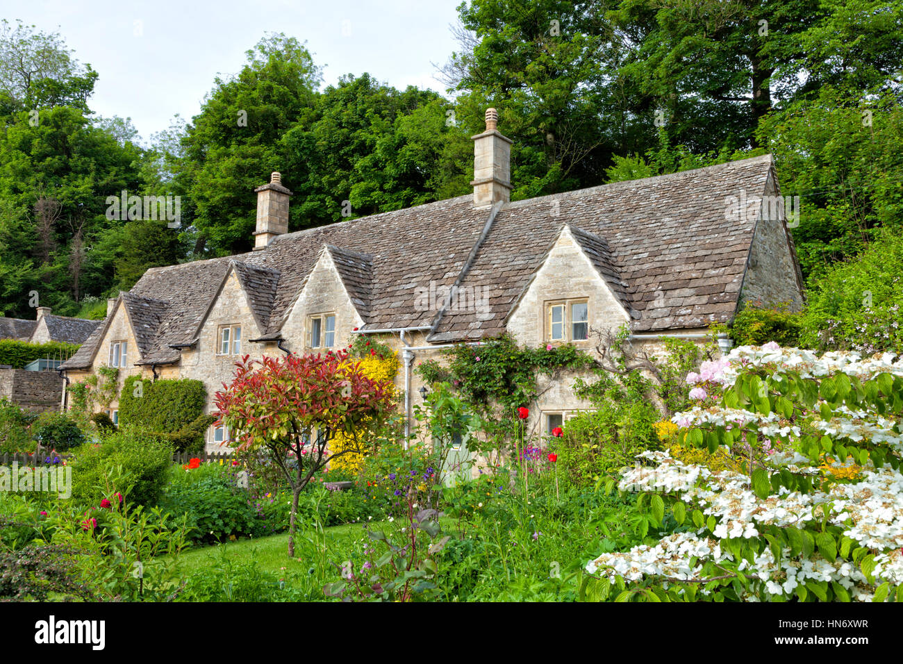 Traditional English limestone cottages with colorful, flowering summer ...