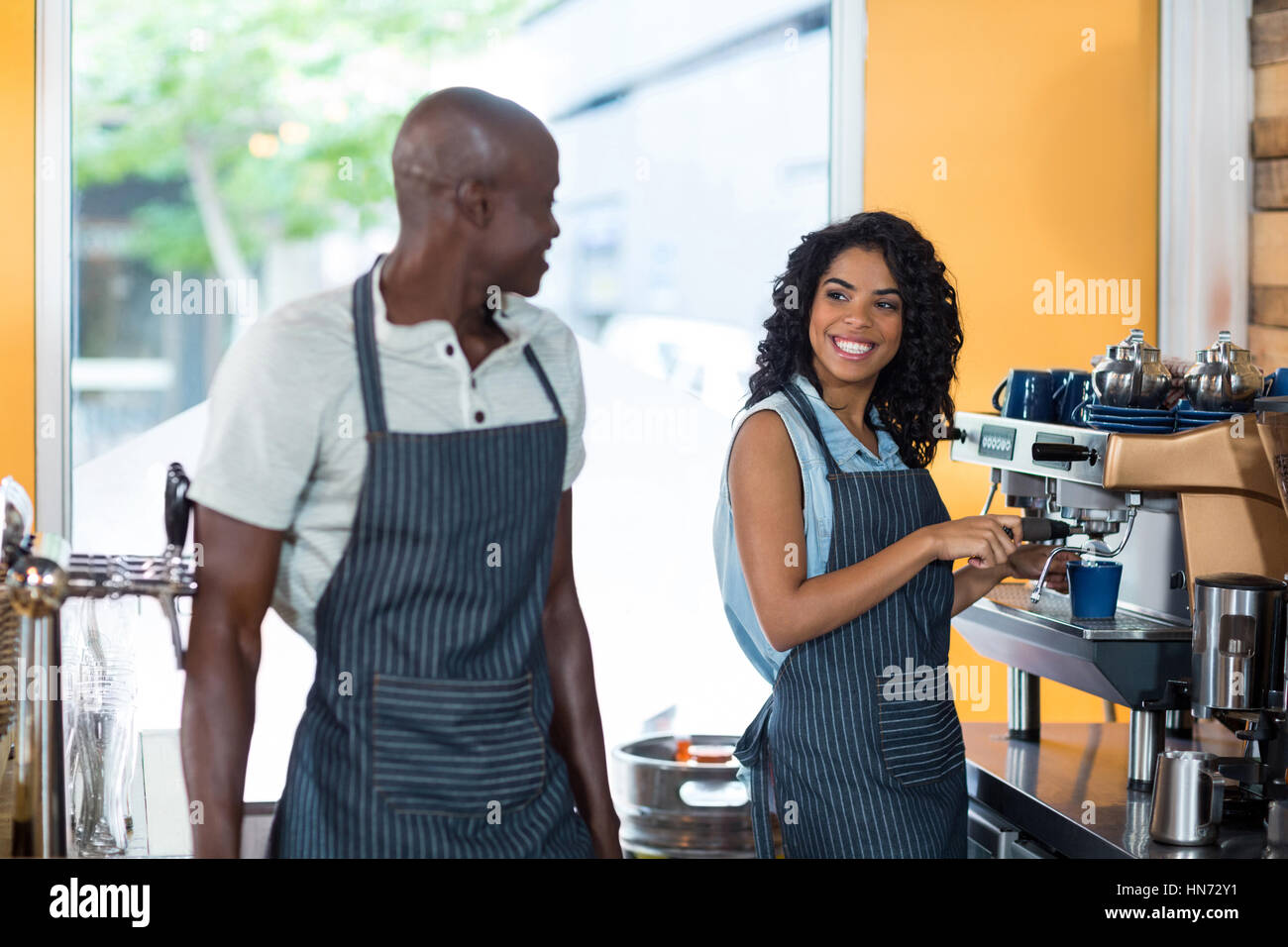 Smiling waitress and waiter interacting while working at counter in ...