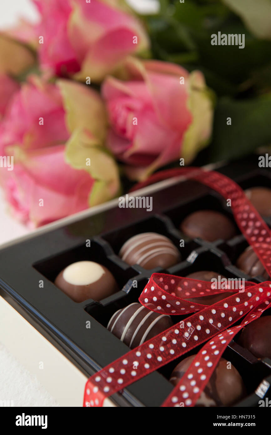 Bunch of roses and assorted chocolate box against white background ...