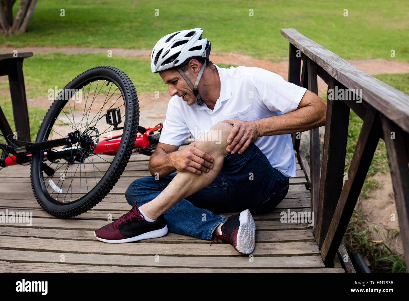 Fallen cyclist holding his injured knee in park Stock Photo - Alamy