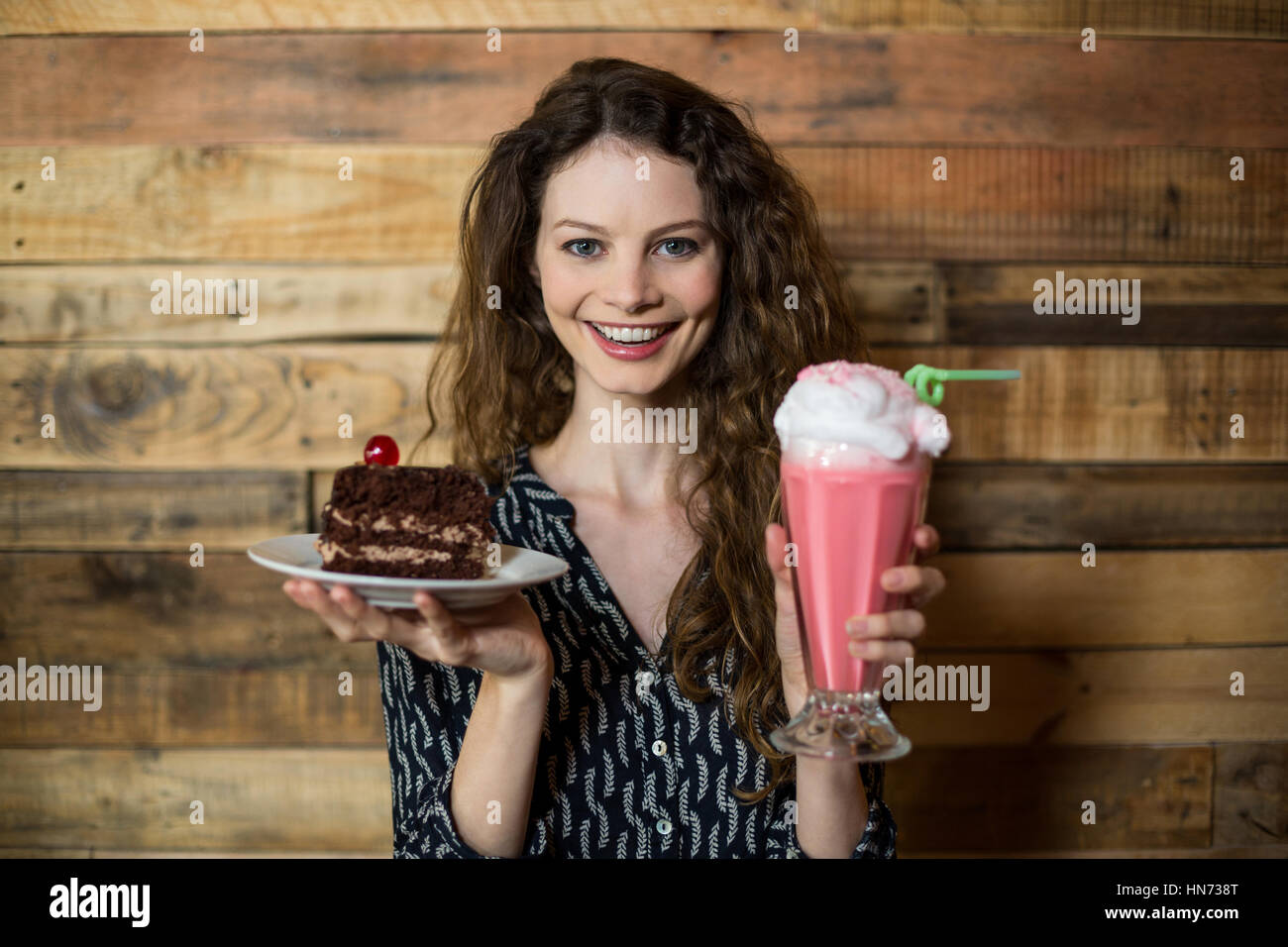 Portrait of woman standing with glass of milkshake and pastry in cafÃƒÂ ...