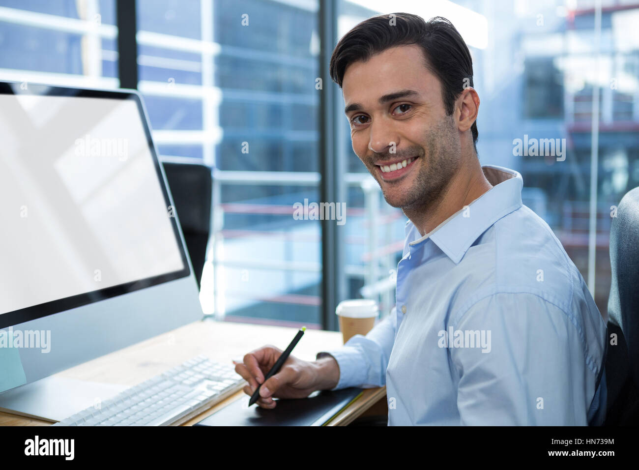 Portrait of male graphic designer using graphics tablet at desk in ...