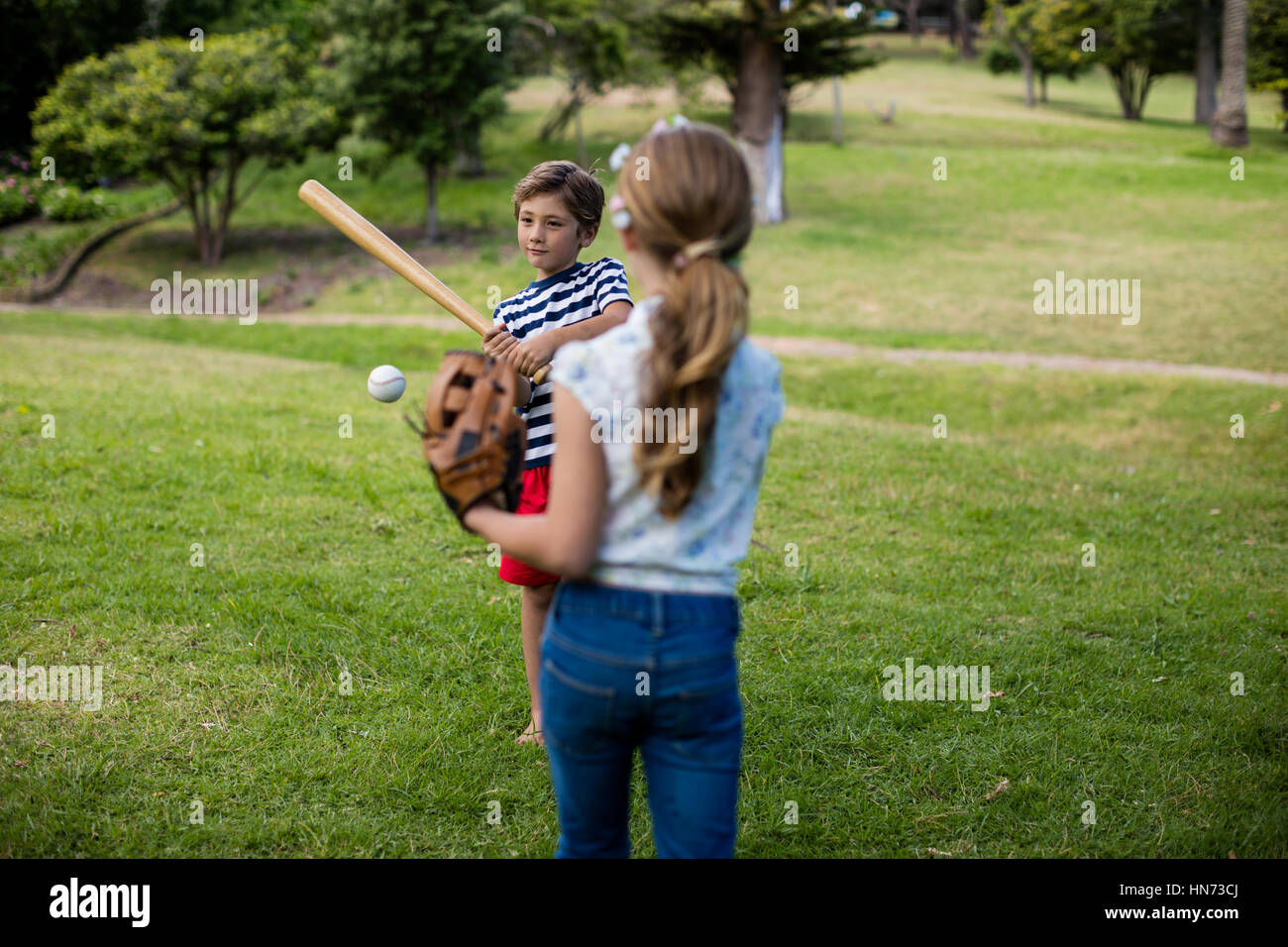 Boy and girl playing baseball in park Stock Photo - Alamy