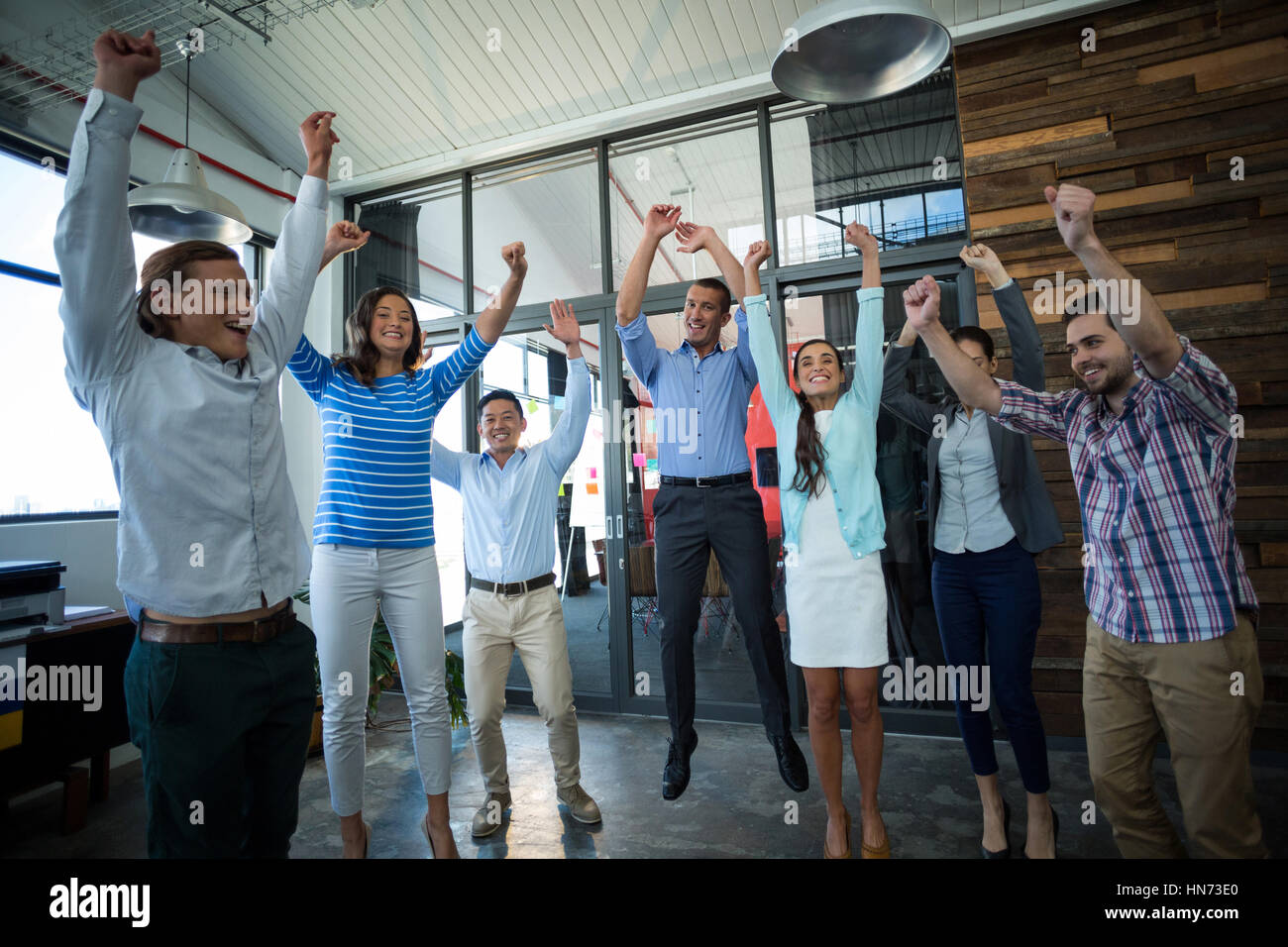 Team of excited businesspeople jumping in office Stock Photo - Alamy