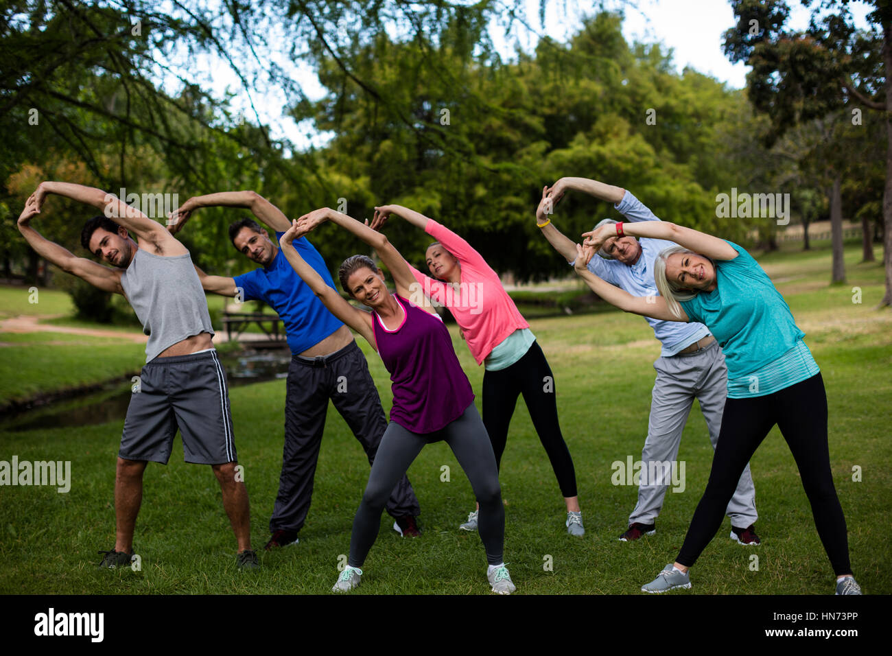 Group of people performing stretching exercise in park Stock Photo - Alamy