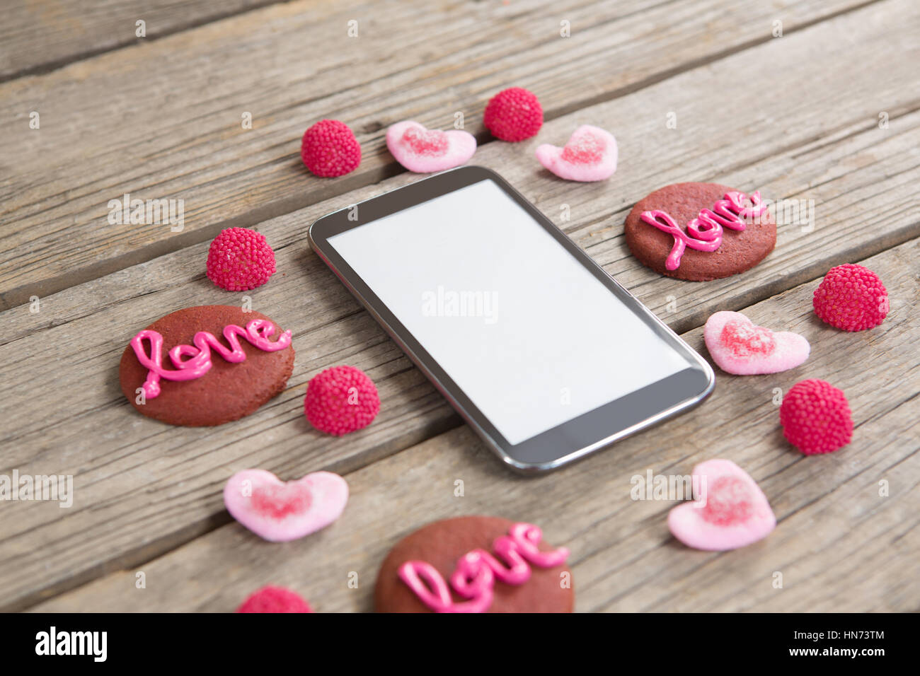 Mobile phone surrounded with cookies and confectionery displaying love ...