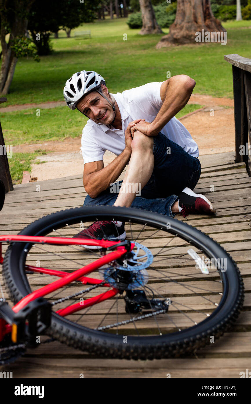 Fallen cyclist holding his injured knee in park Stock Photo - Alamy