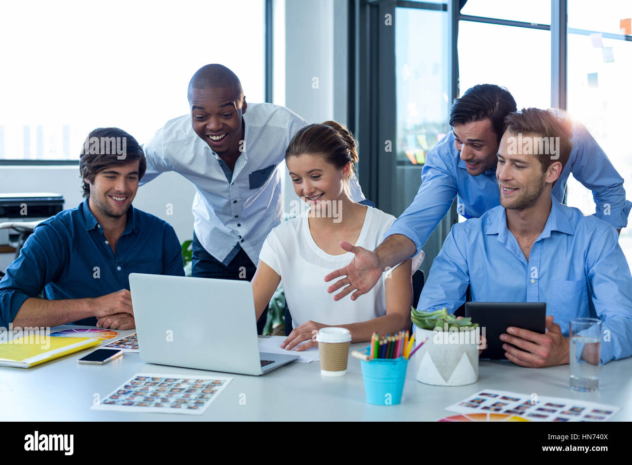 Team of graphic designers discussing over laptop in office Stock Photo ...