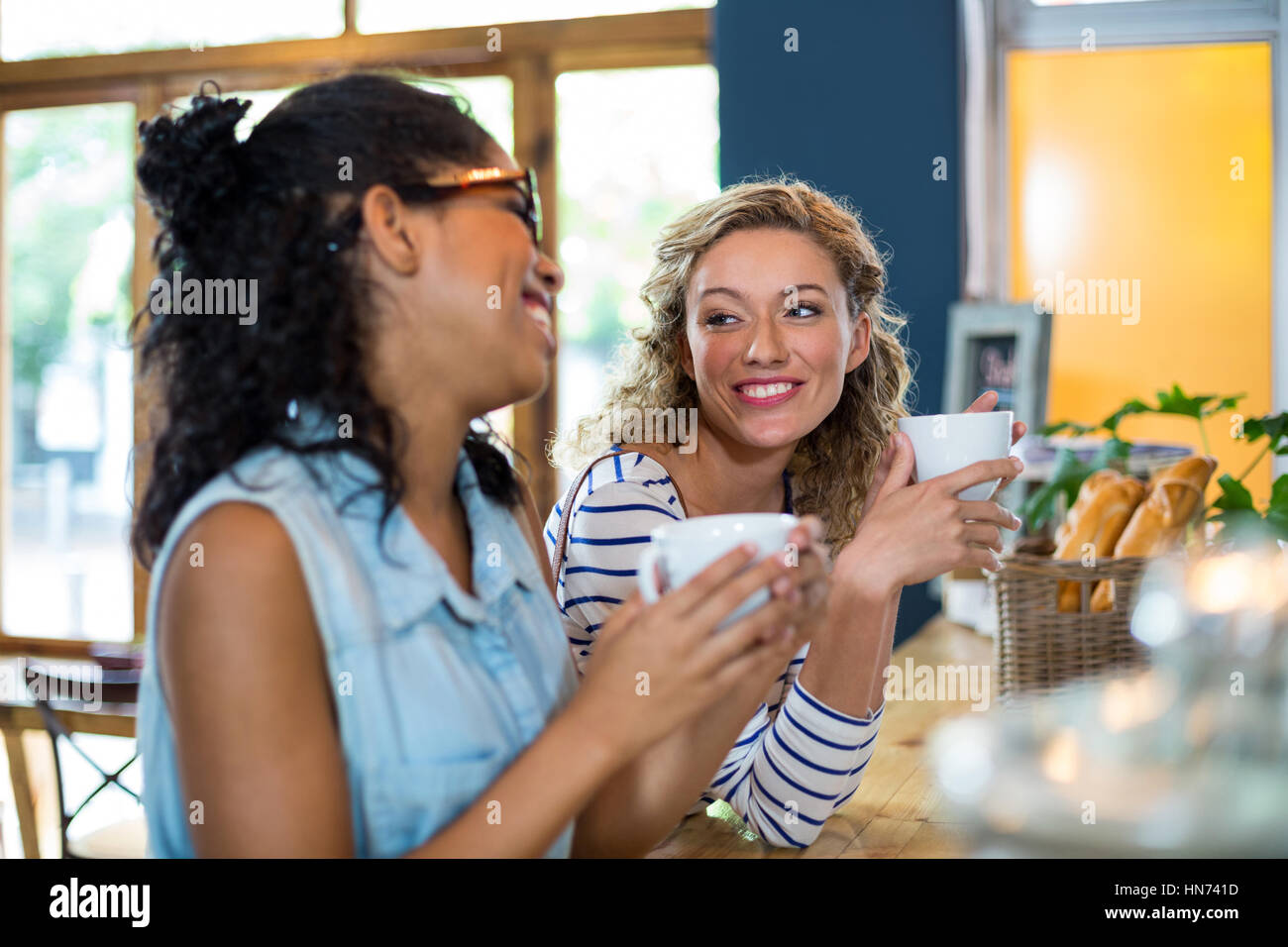 Two female friends interacting while having coffee in cafÃƒÂ© Stock ...