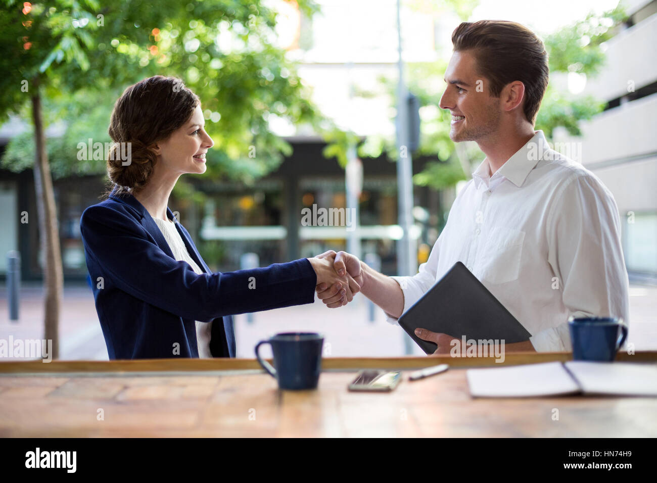 Businesswoman shaking hands with businessman at counter in cafe Stock ...