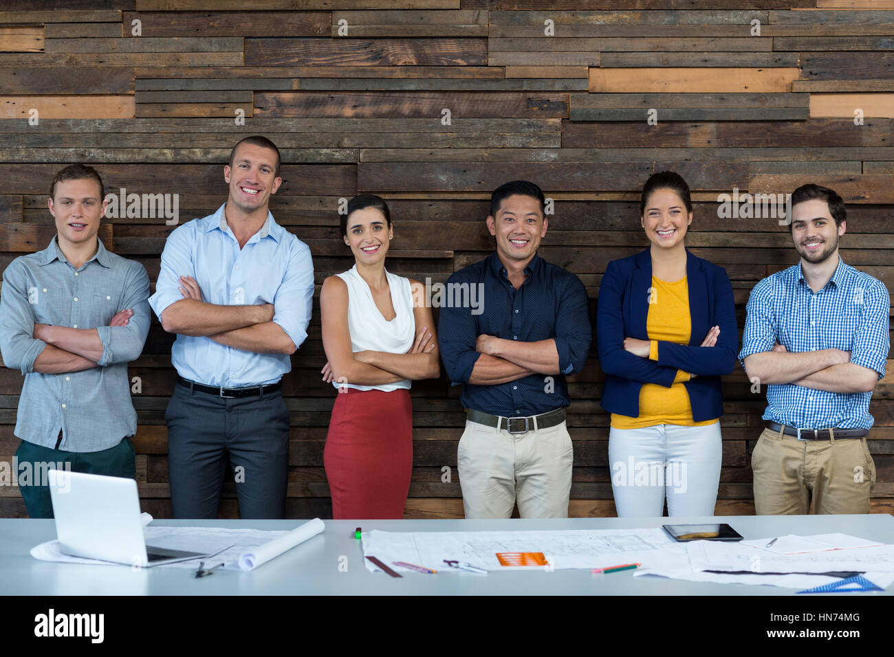Portrait of smiling business executives standing with arms crossed in ...