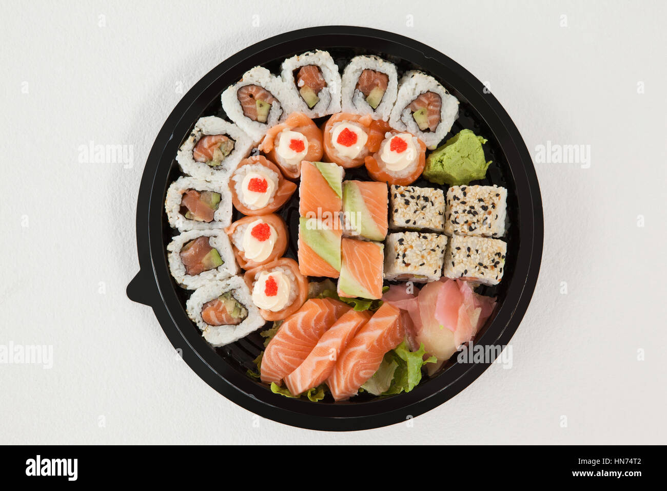 Set of assorted sushi kept in a round black box against white ...